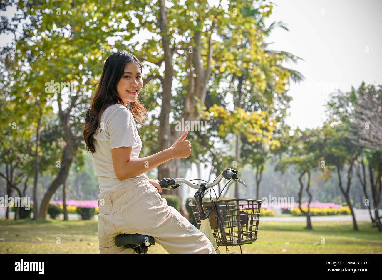 Happy and chill young Asian woman in casual clothes is on a bike in the ...