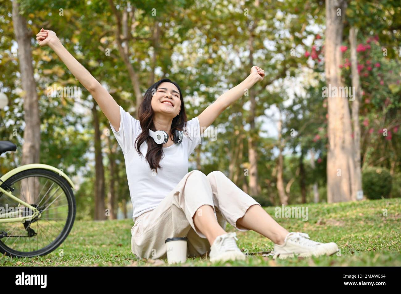 Chilling young Asian woman in casual comfy clothes raising hands ...