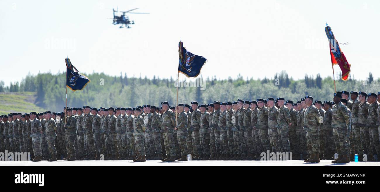 Soldiers stand in formation as an AH-64 Apache helicopter flies ...