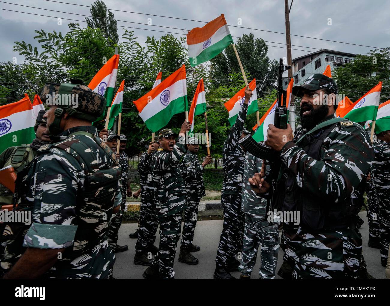 Indian paramilitary soldiers hold national flags and shout slogans as ...