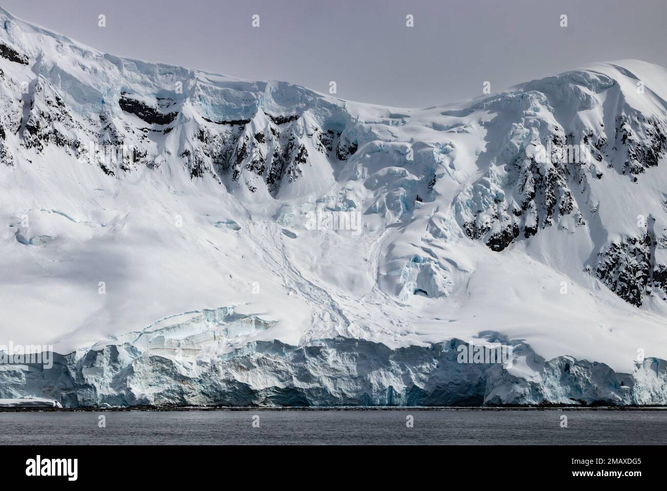 Tall mountain ridge on Antarctic Peninsula, topped by steep cliffs with ...