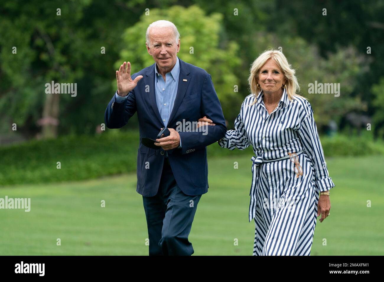 President Joe Biden with first lady Jill Biden waves as they walk on ...
