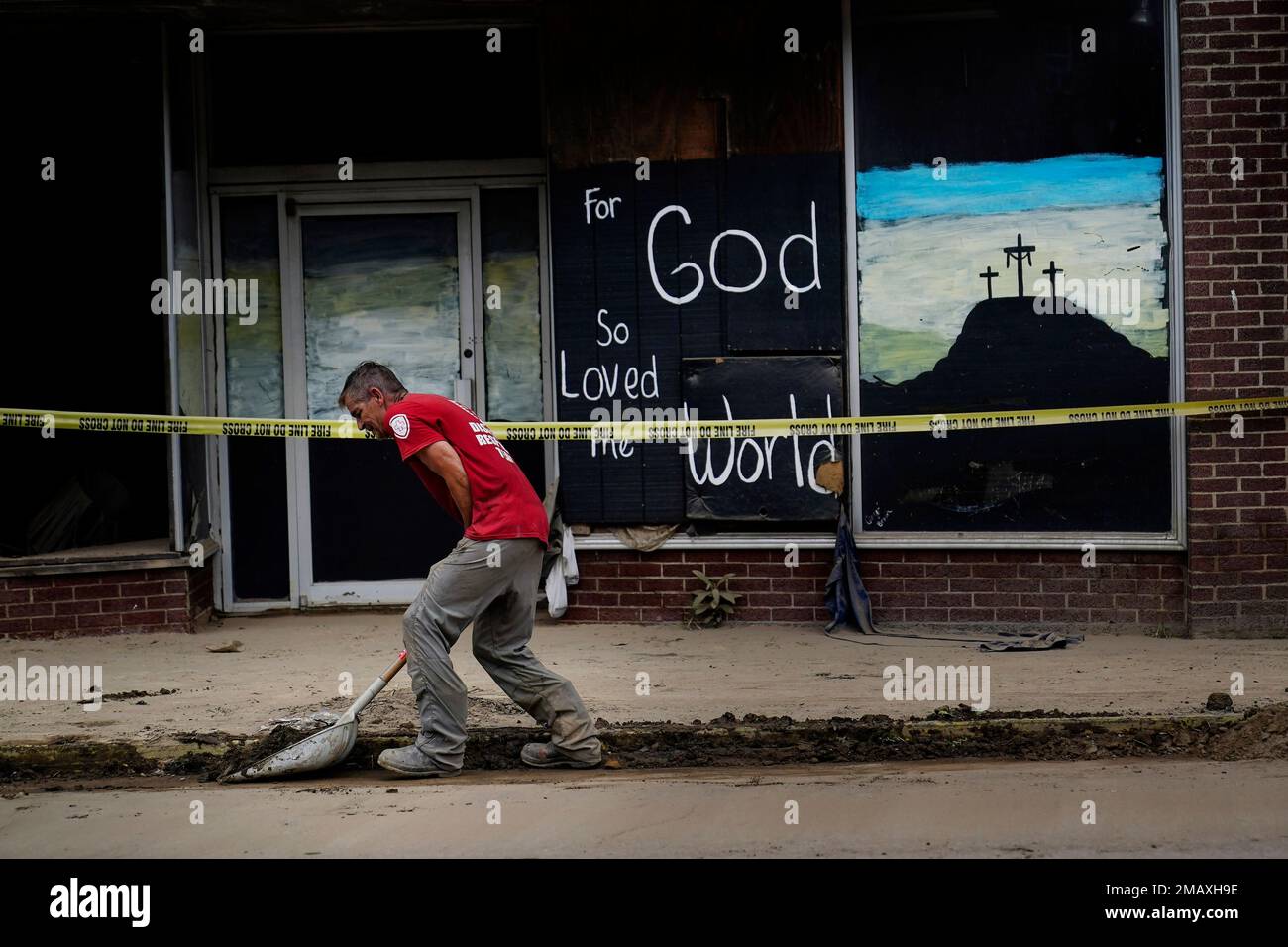 A volunteer shovels dirt and debris off of the main street in downtown ...