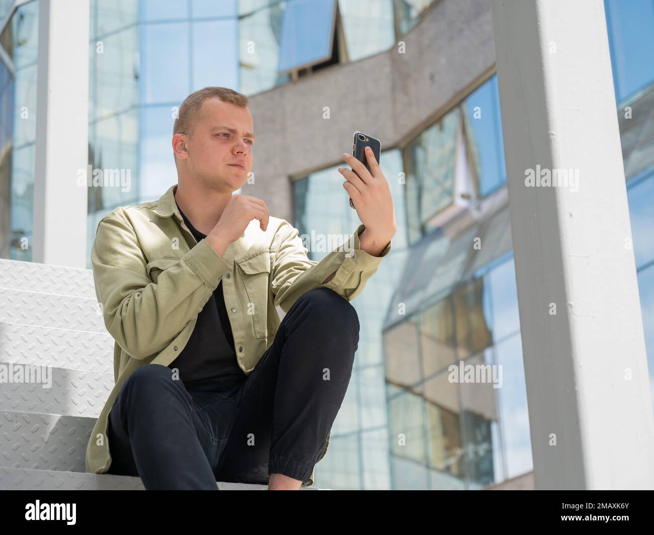 Young man sitting on the stairs and talking sign language via video ...