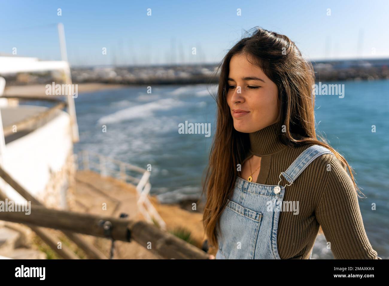 Hispanic female with long hair closing eyes delightfully while standing ...