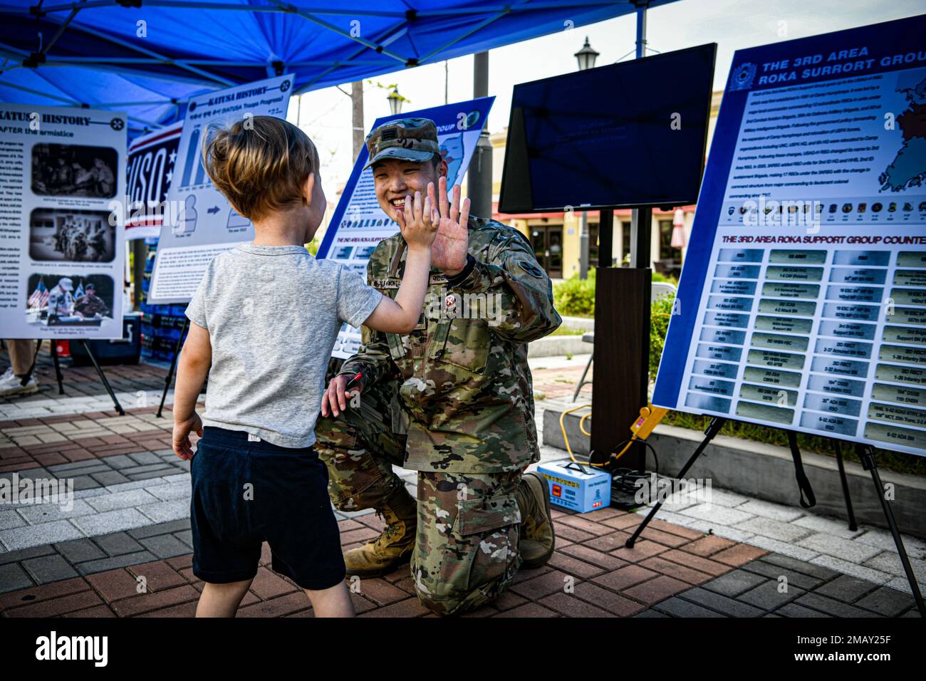A KATUSA high-fives a child at a booth detailing the history of the ...