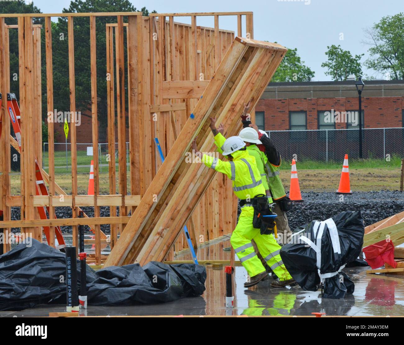 Contractors use teamwork to raise one of the walls of one set of ...