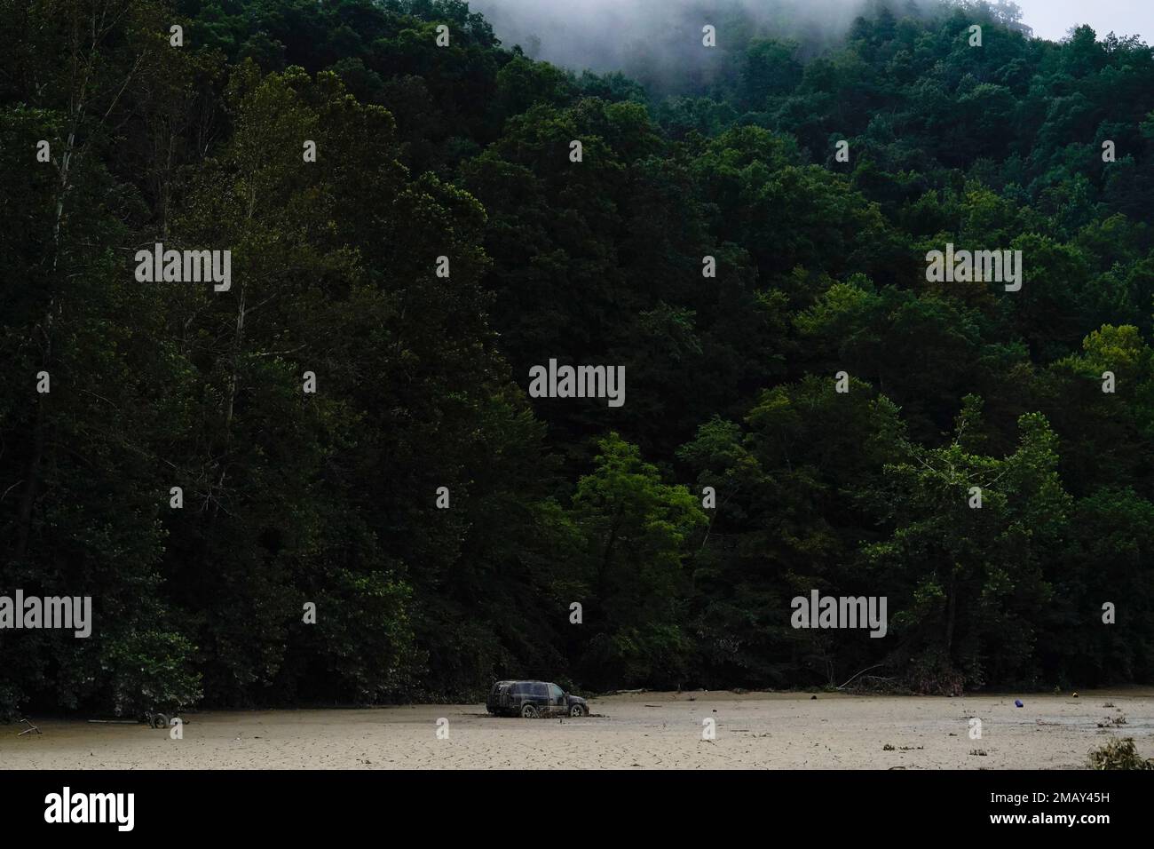 A vehicle is abandoned and surrounded by mud caused by massive flooding ...