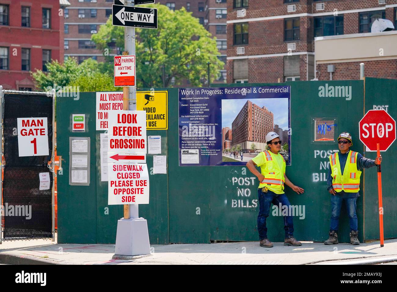 Construction workers help direct traffic outside a residential and ...