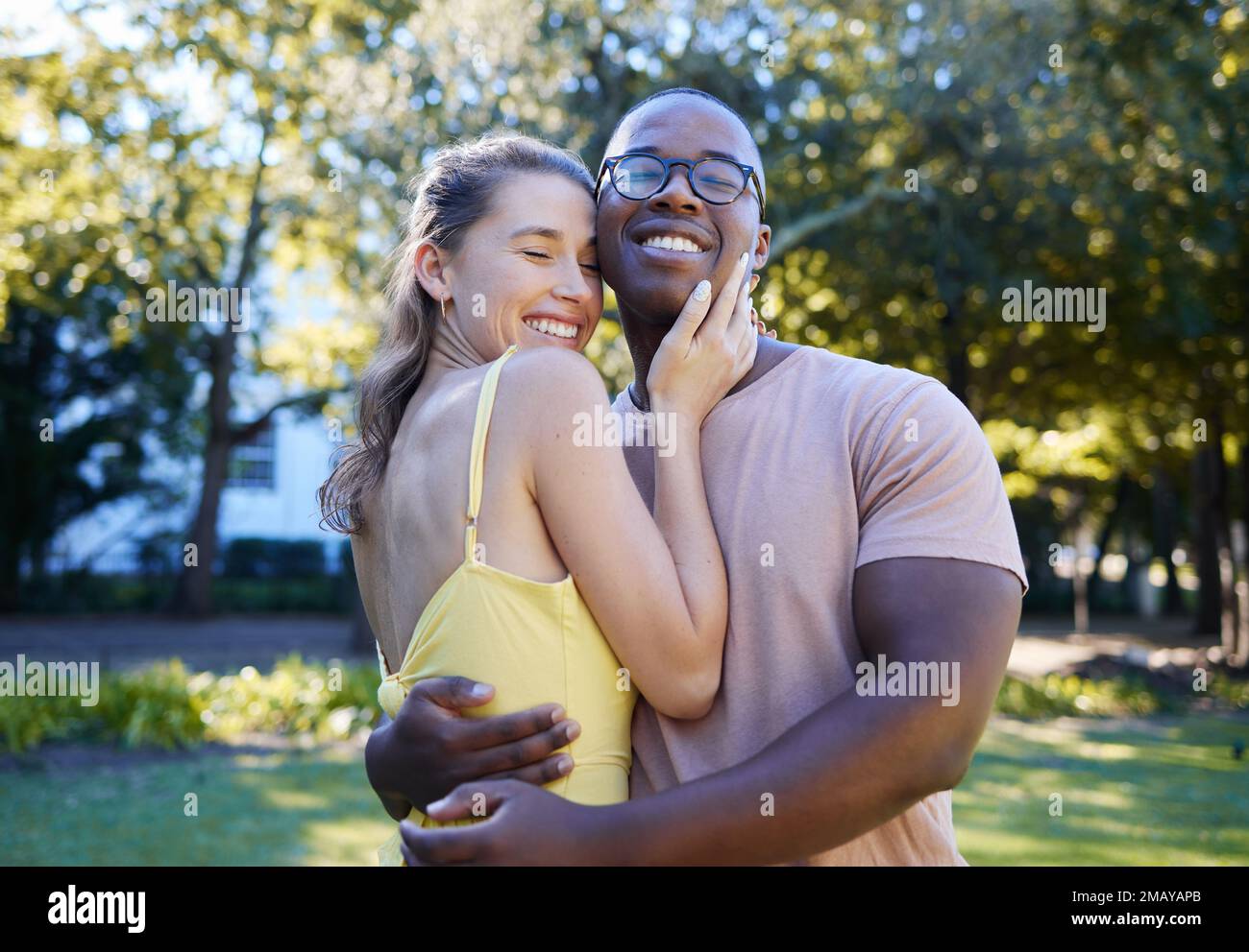 Love, interracial and couple hug in park, bonding and happiness for ...