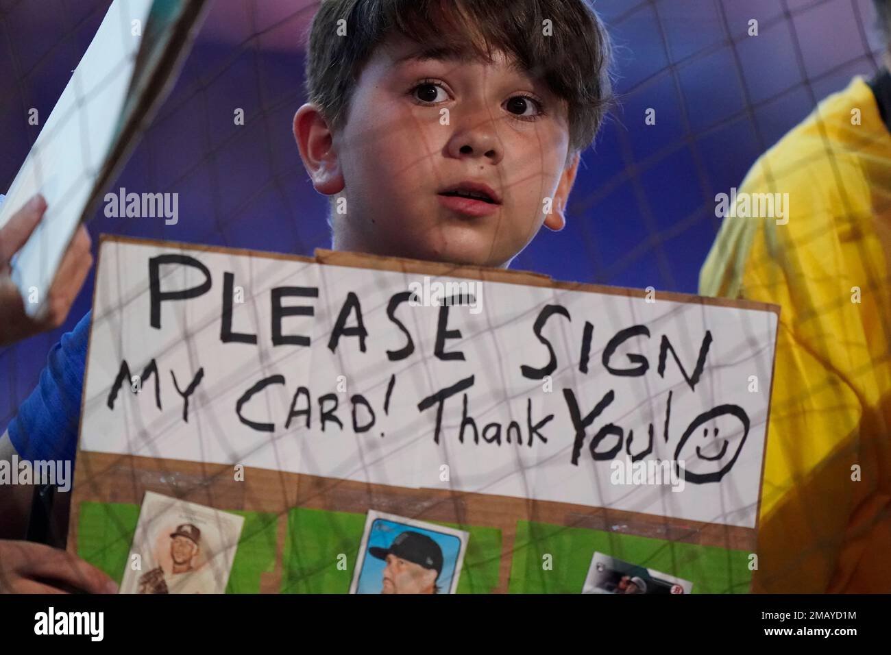 A young baseball fan looks players to sign his cards before the start ...