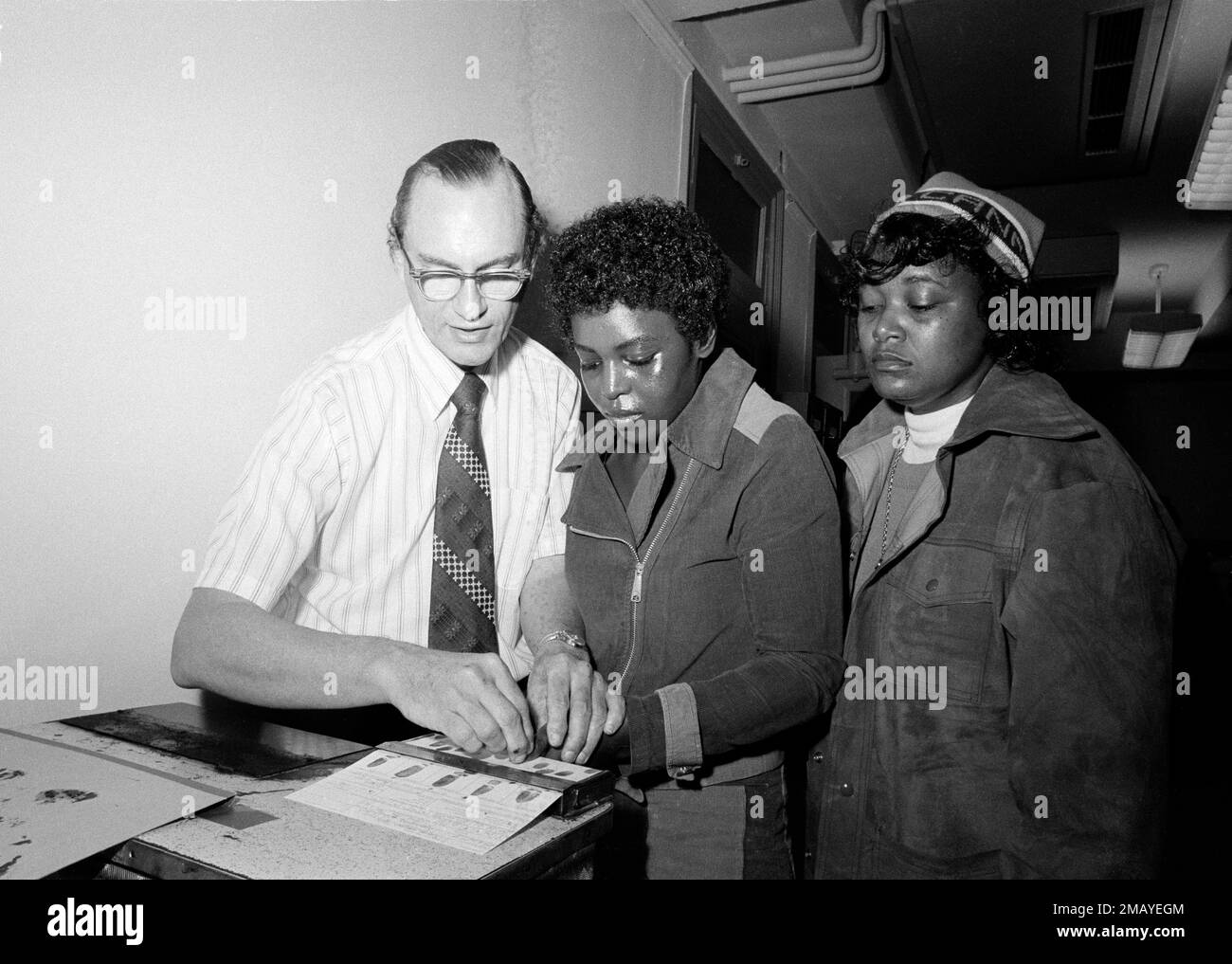 Marian Tyger Trimiar, center, is fingerprinted in New York City by ...