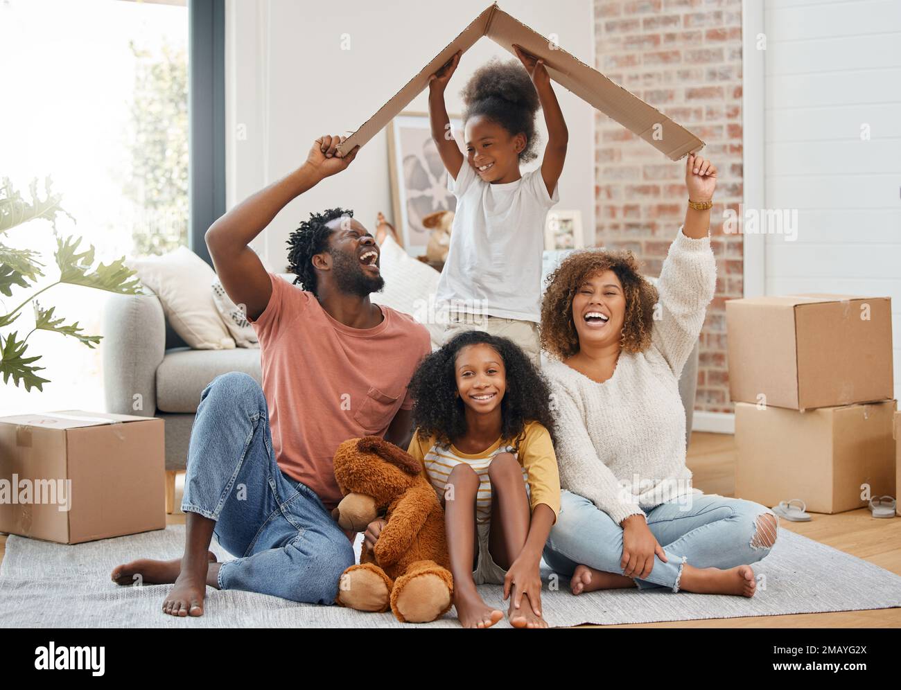 A family affair. a young family holding up a cardboard box to form a ...