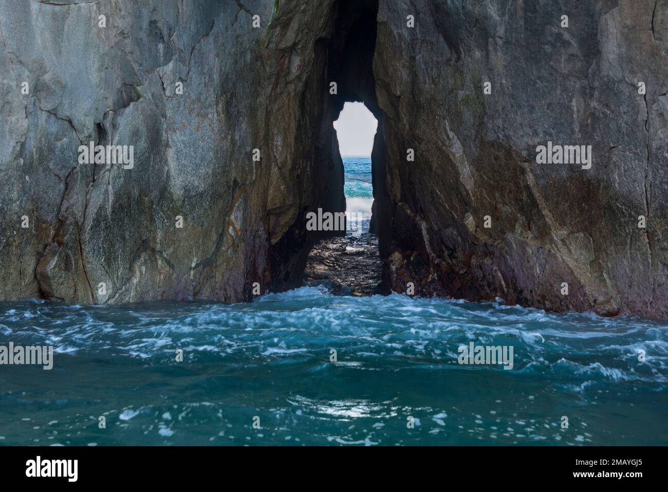 A hole in the rock wall at Land's End on the Baja Peninsula, connecting ...