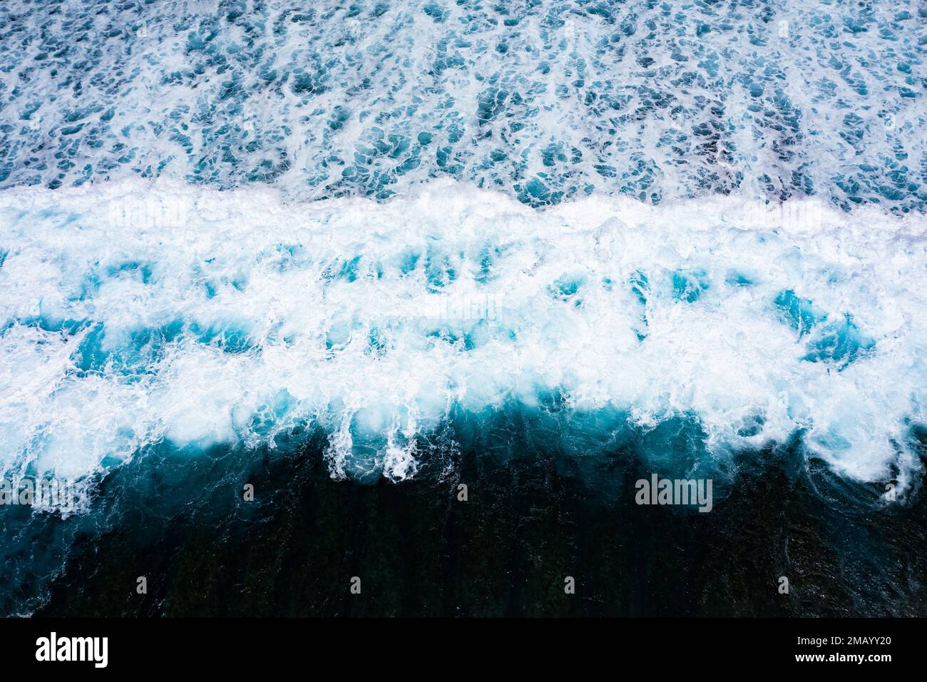 Stunning aerial view of some ocean waves breaking on a blue sea ...