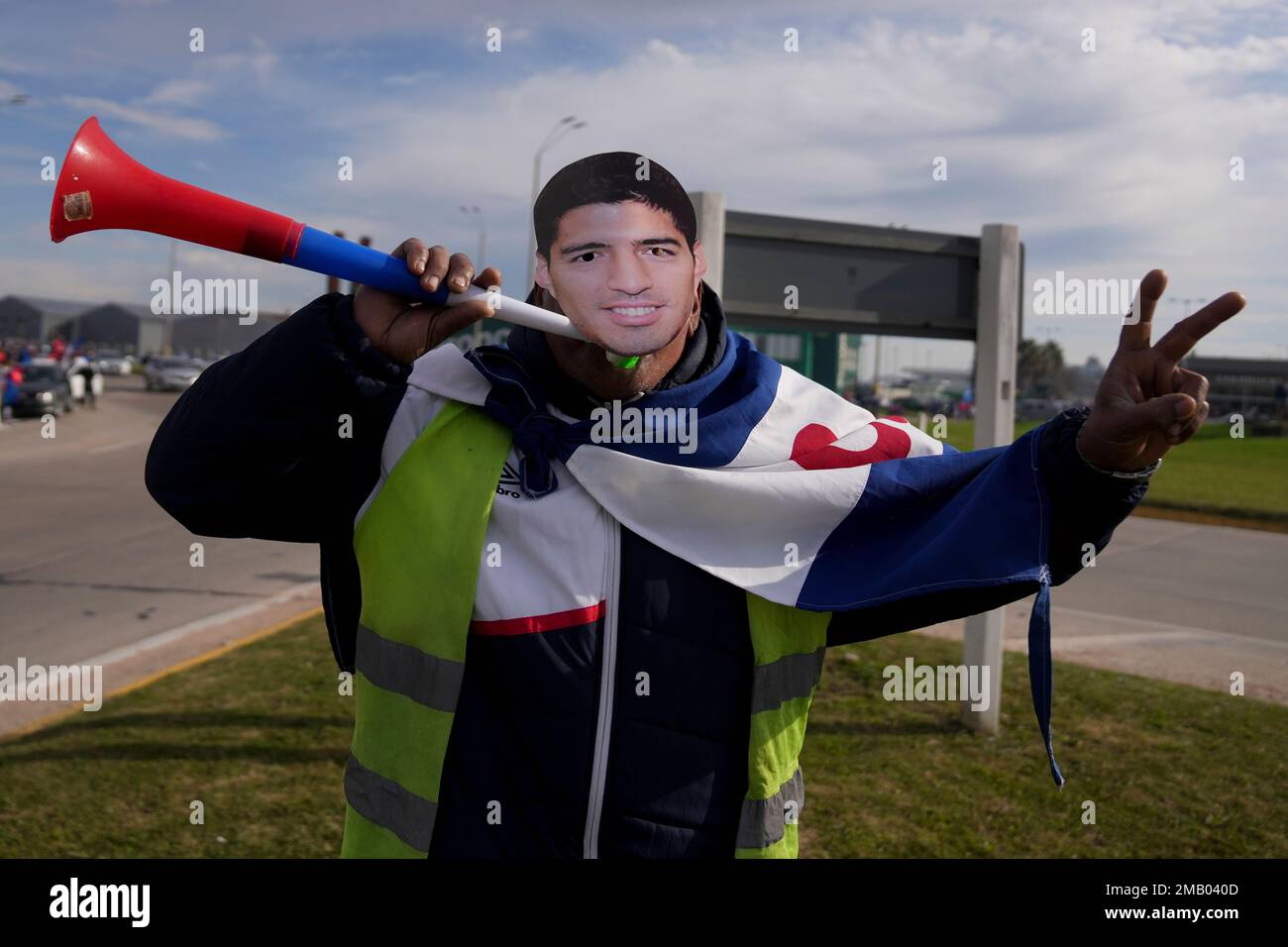 A fan wearing a mask with the visage of soccer star Luis Suarez waits ...
