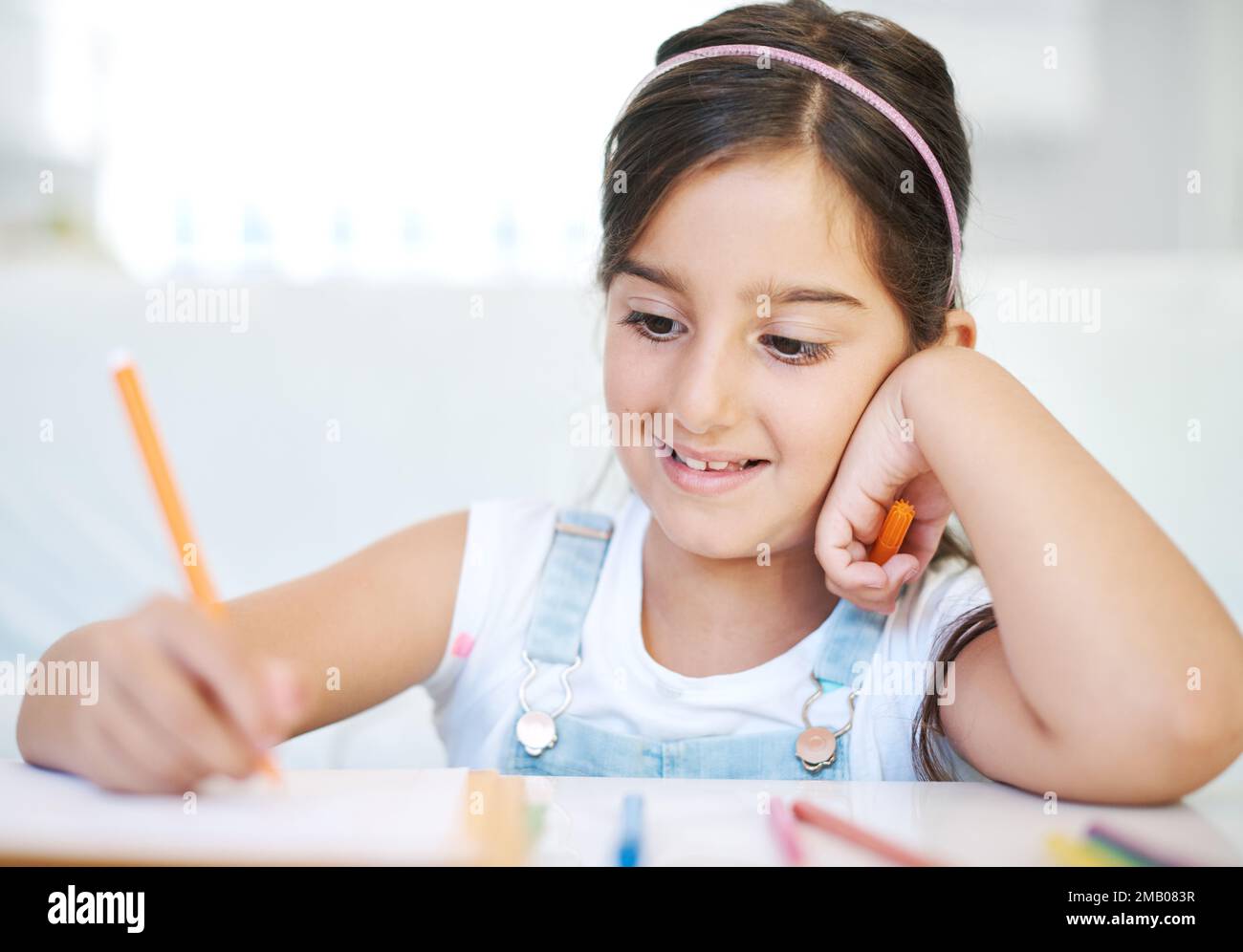 Orange is my favourite colour. a little girl writing in a book at home ...