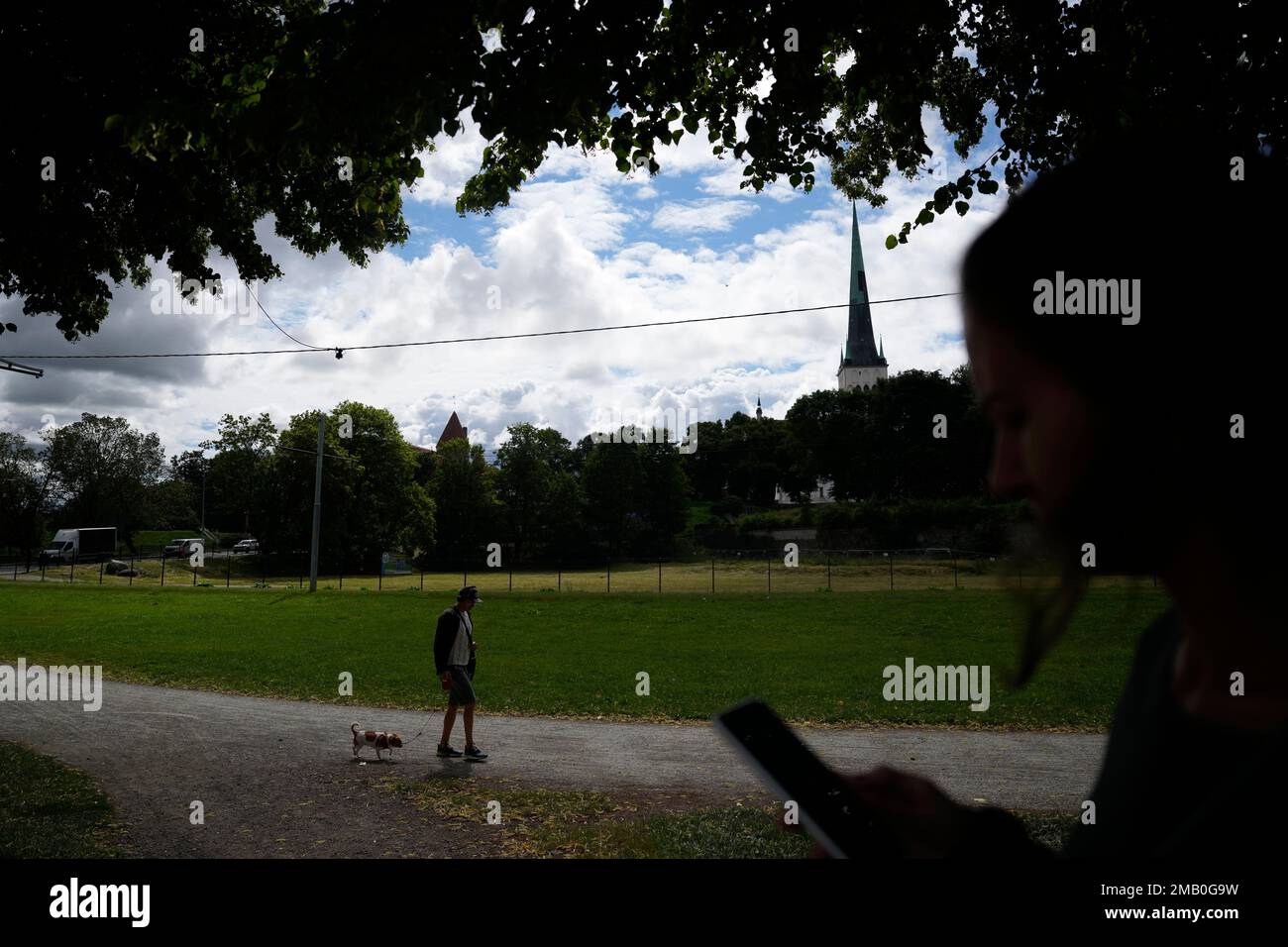 A man walks a dog, with St. Olaf's Church tower in the background, in ...