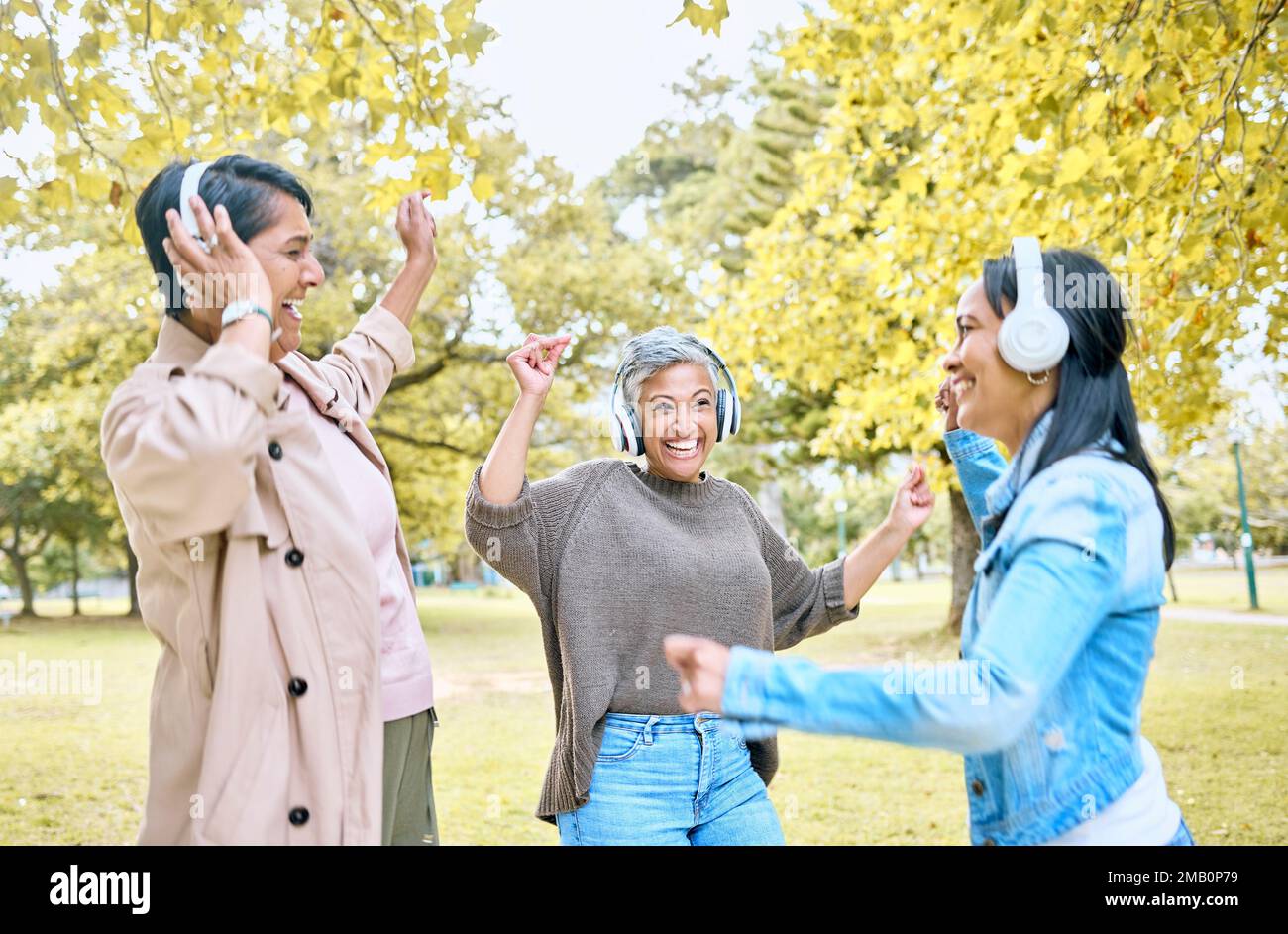 Music headphones, friends and women dance at park outdoors. Senior ...