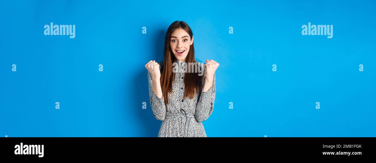 Excited woman looking relieved and hopeful, making fist pump and ...