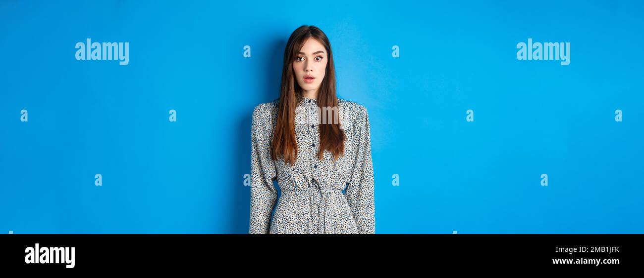Shocked caucasian woman with long hair, wearing dress, gasping and ...