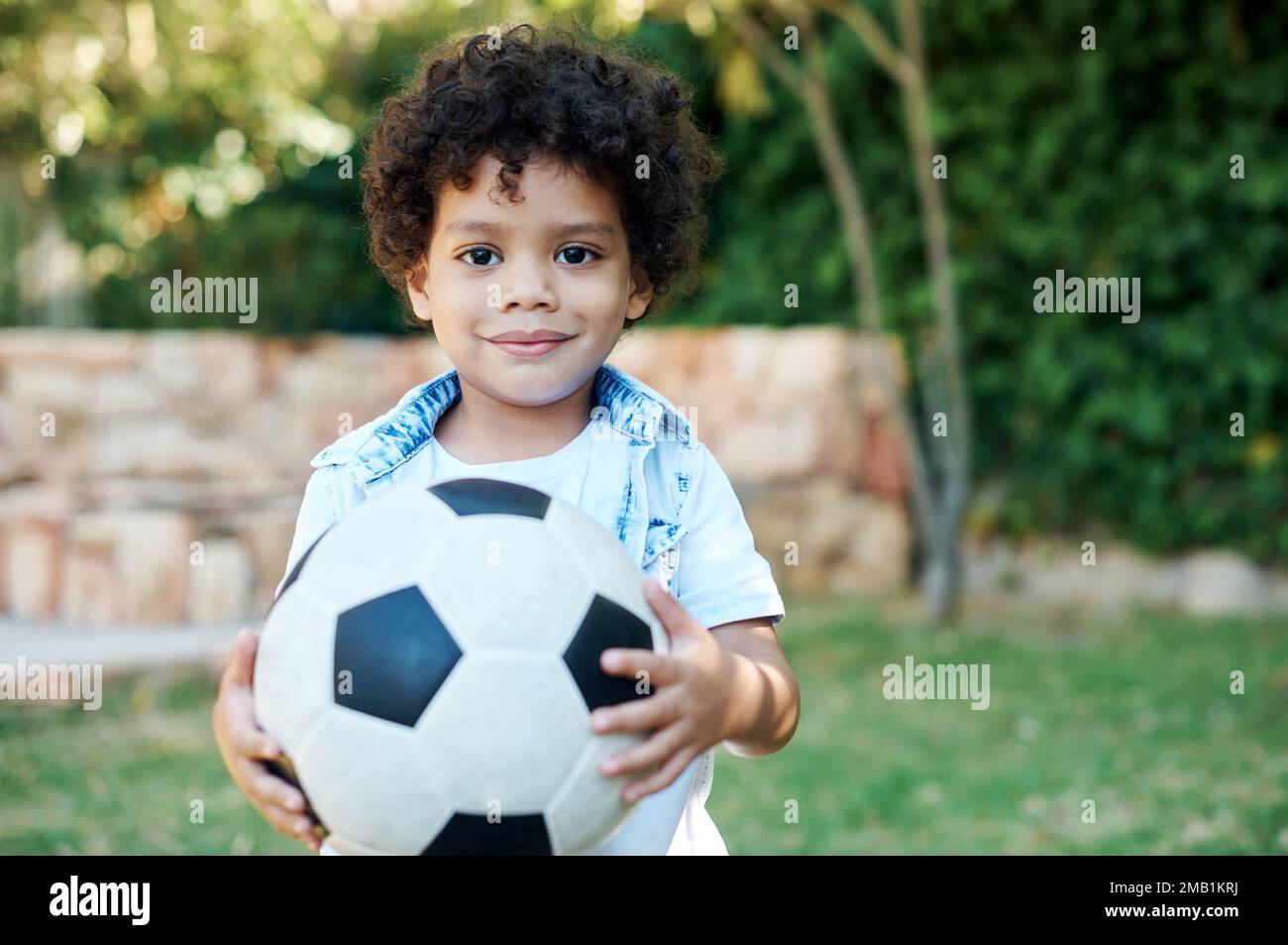Come play ball with me. an adorable little boy holding a ball Stock ...