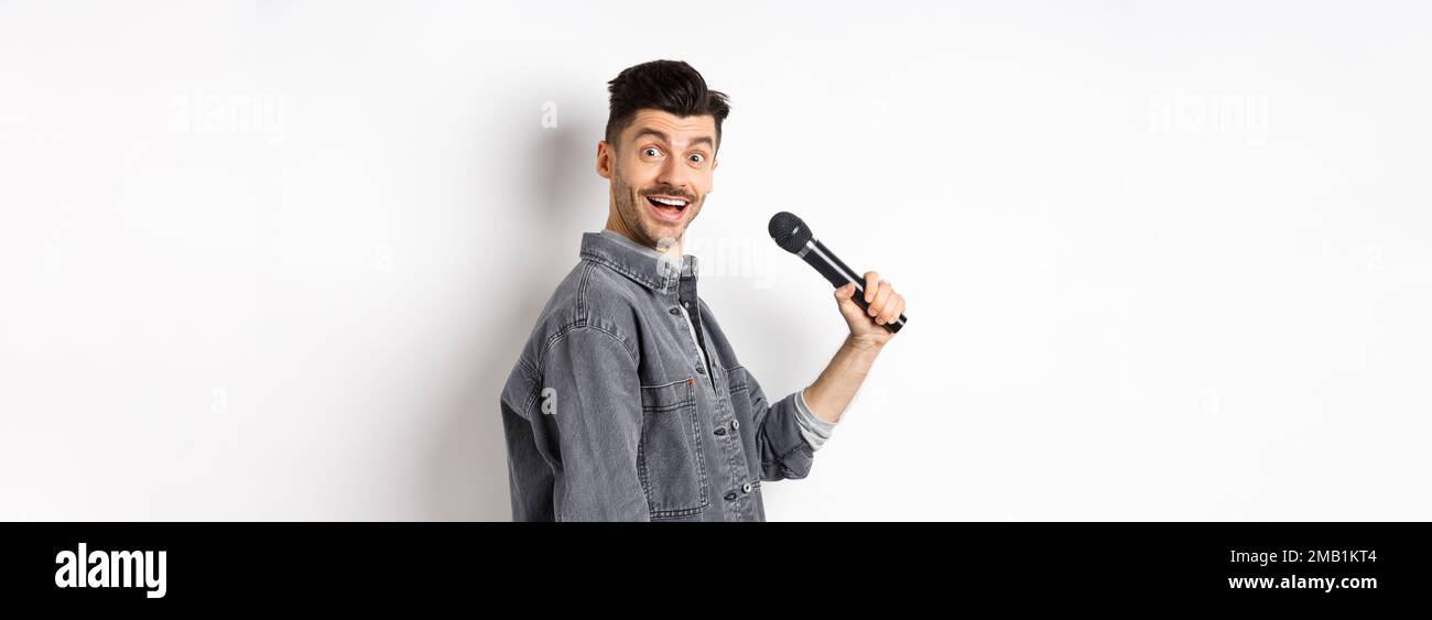 Profile of handsome smiling man holding mic, turn head at camera with ...