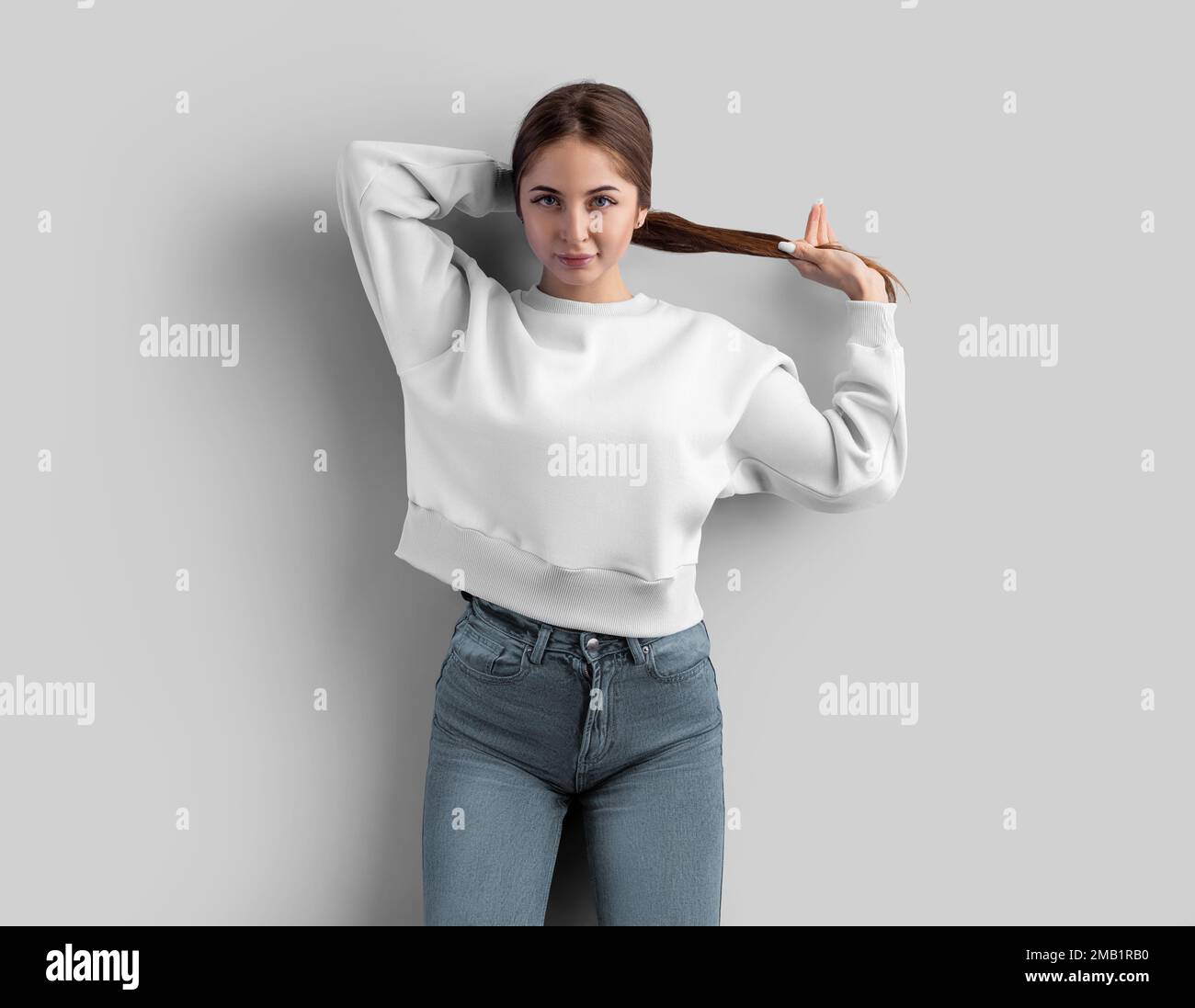 Mockup of a white crop sweatshirt on a girl in gray jeans, holds her ...