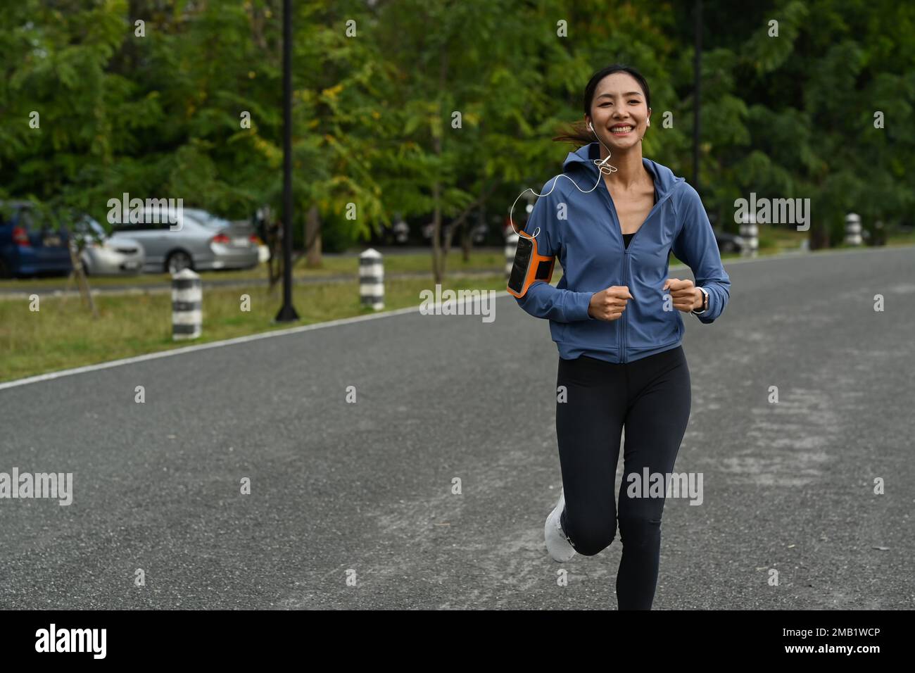 Active young asian woman in sportswear running in the public park ...