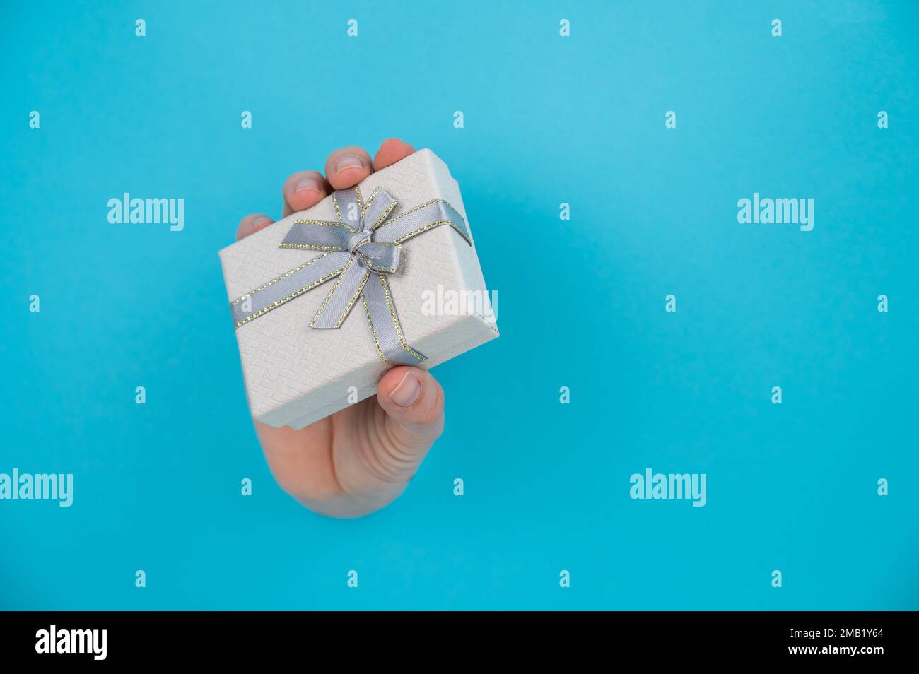 A woman's hand sticks out of a blue paper background and a gift box ...
