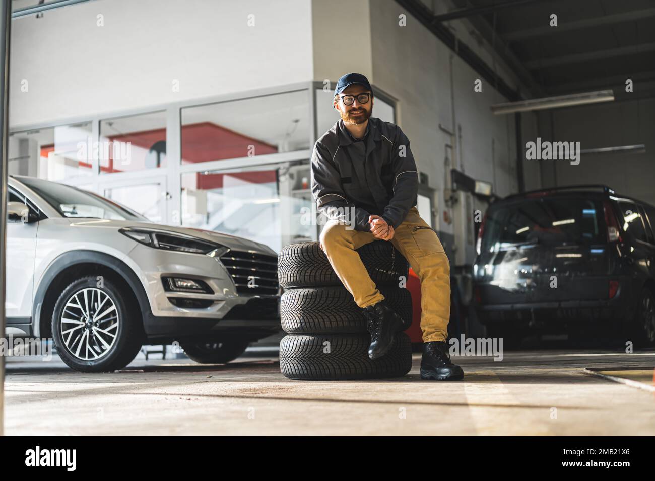 A man sitting on a stack of car wheels in a modern and well-equipped ...