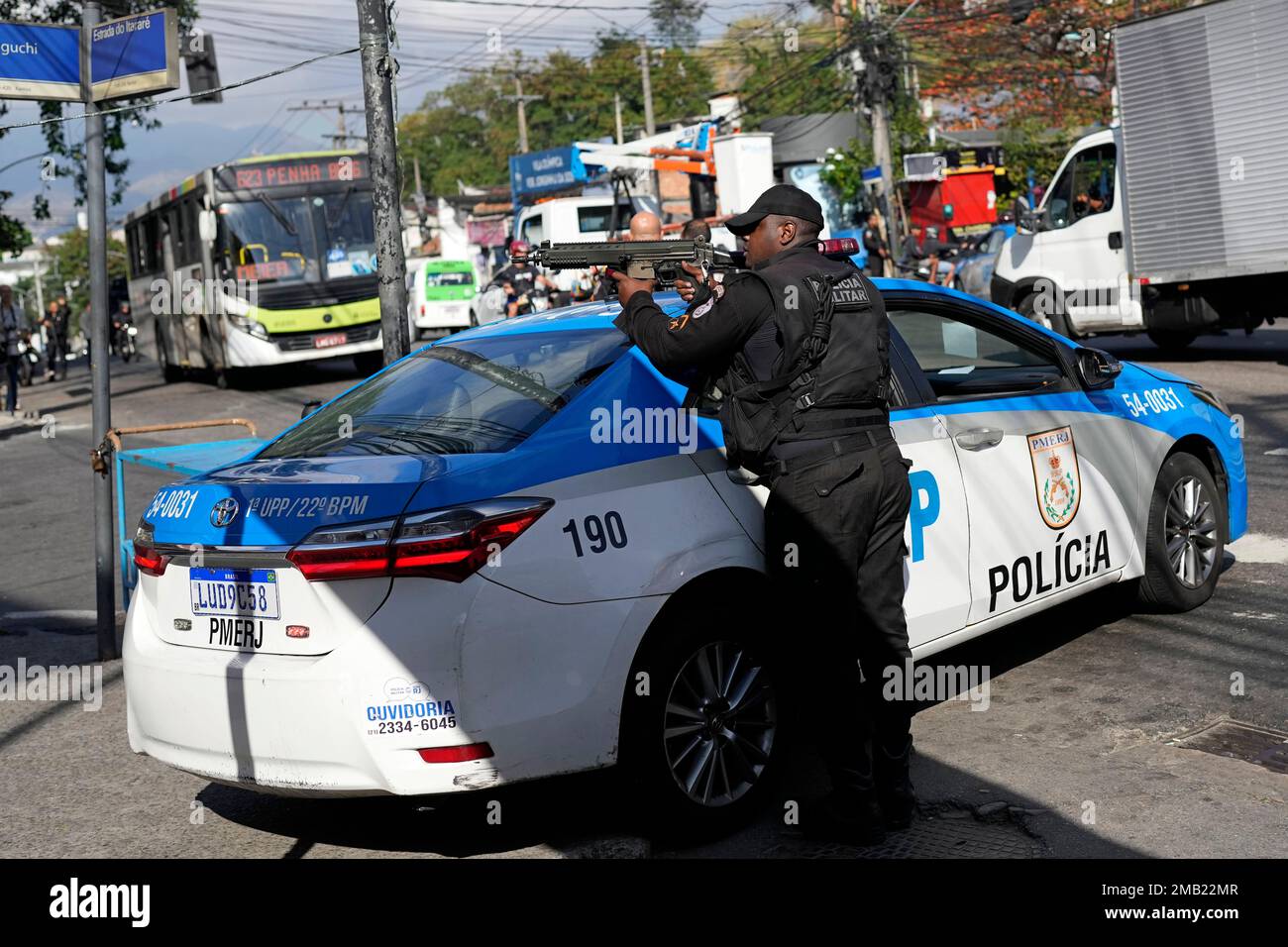 A police officer aims his weapon during an operation in the Complexo do ...