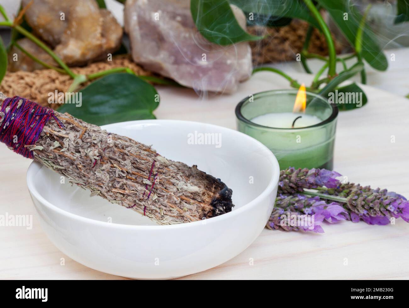 Smudge stick with candle and lavender on a table with plants and ...