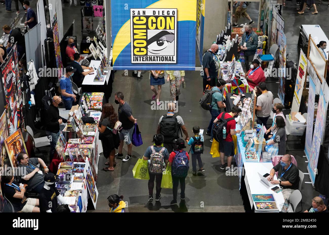 Comic-Con attendees walk down an aisle of the convention show floor ...