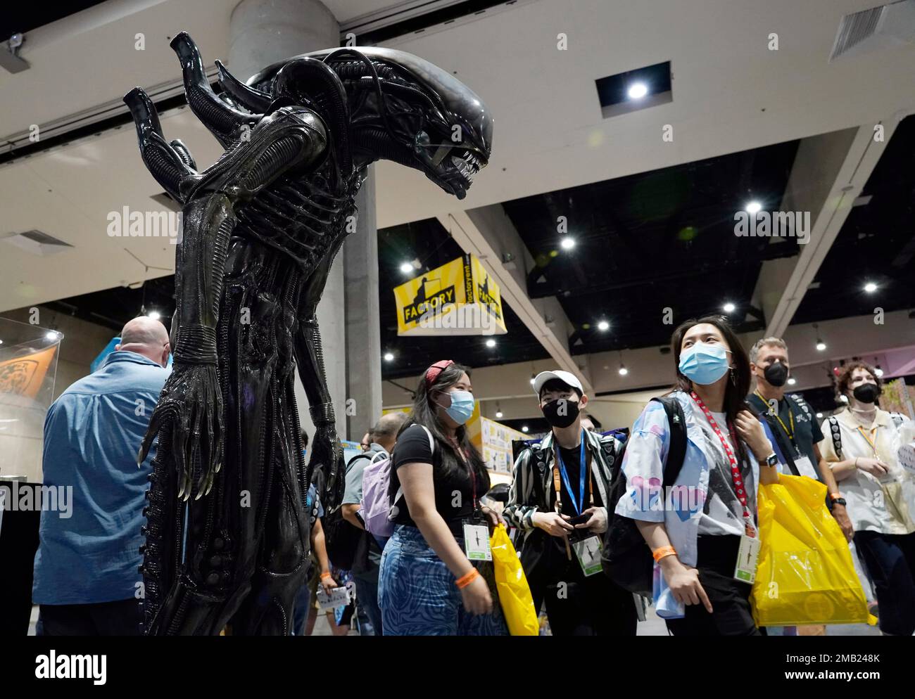 A Comic-Con attendee walks past a life-size model of the creature from ...