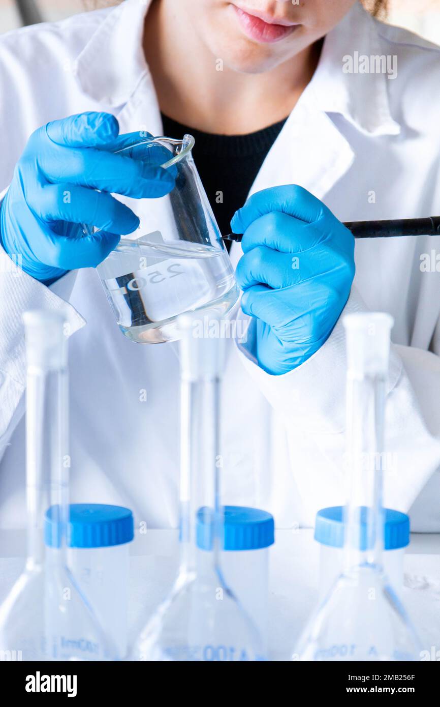 Close up left handed woman scientist labeling beaker samples with blue ...