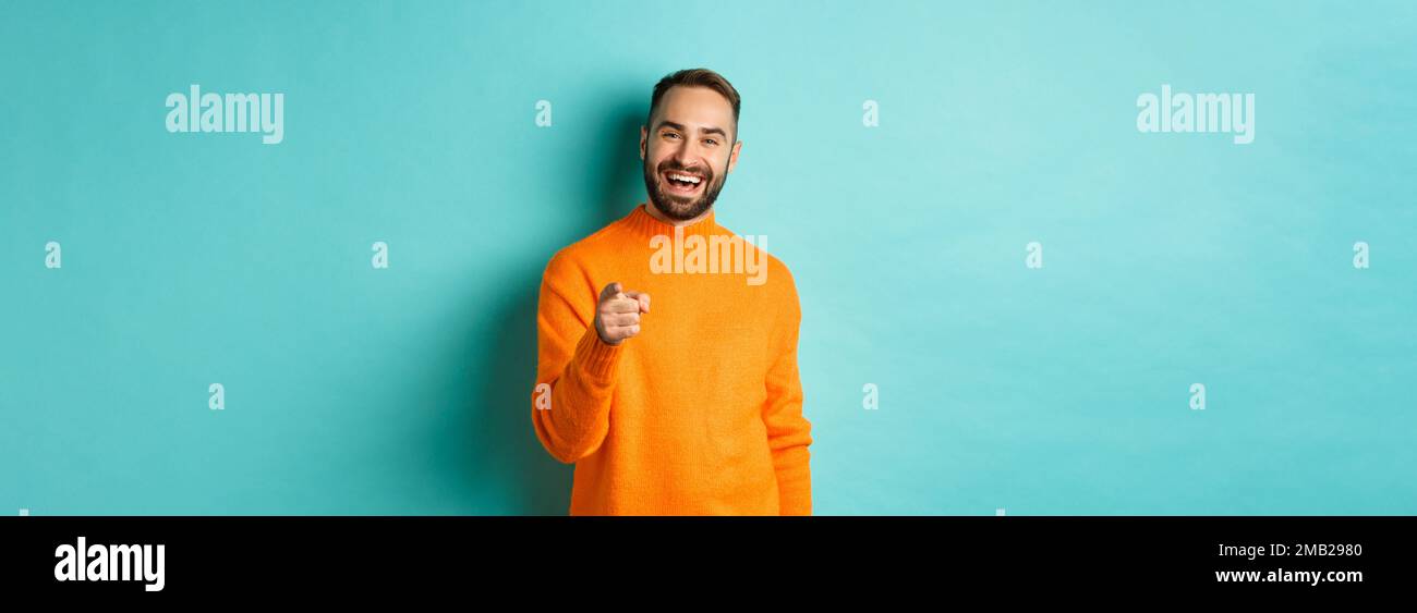 Handsome man laughing and pointing at camera, nodding in approval ...