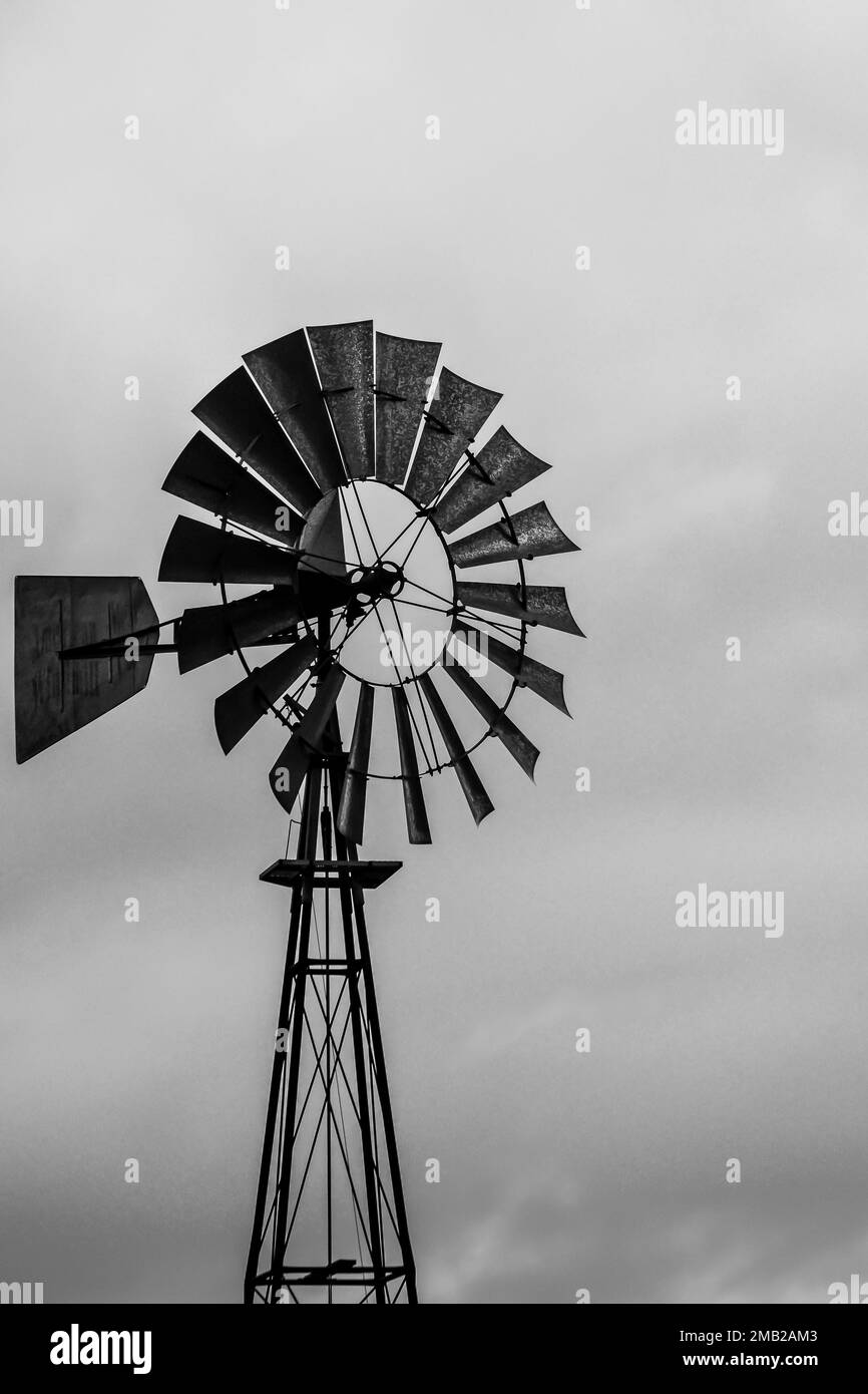 A vertical grayscale shot of an old windmill against a cloudy sky Stock ...