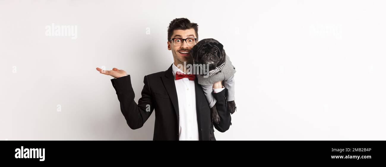 Handsome young man introducing pet product on hand, holding cute black ...