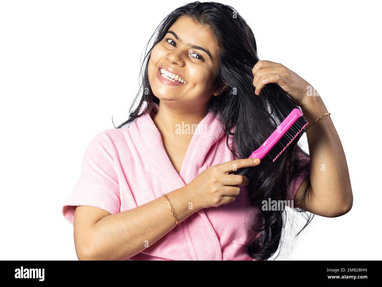 A pretty happy Indian woman brushing hair wearing bathrobe on white ...