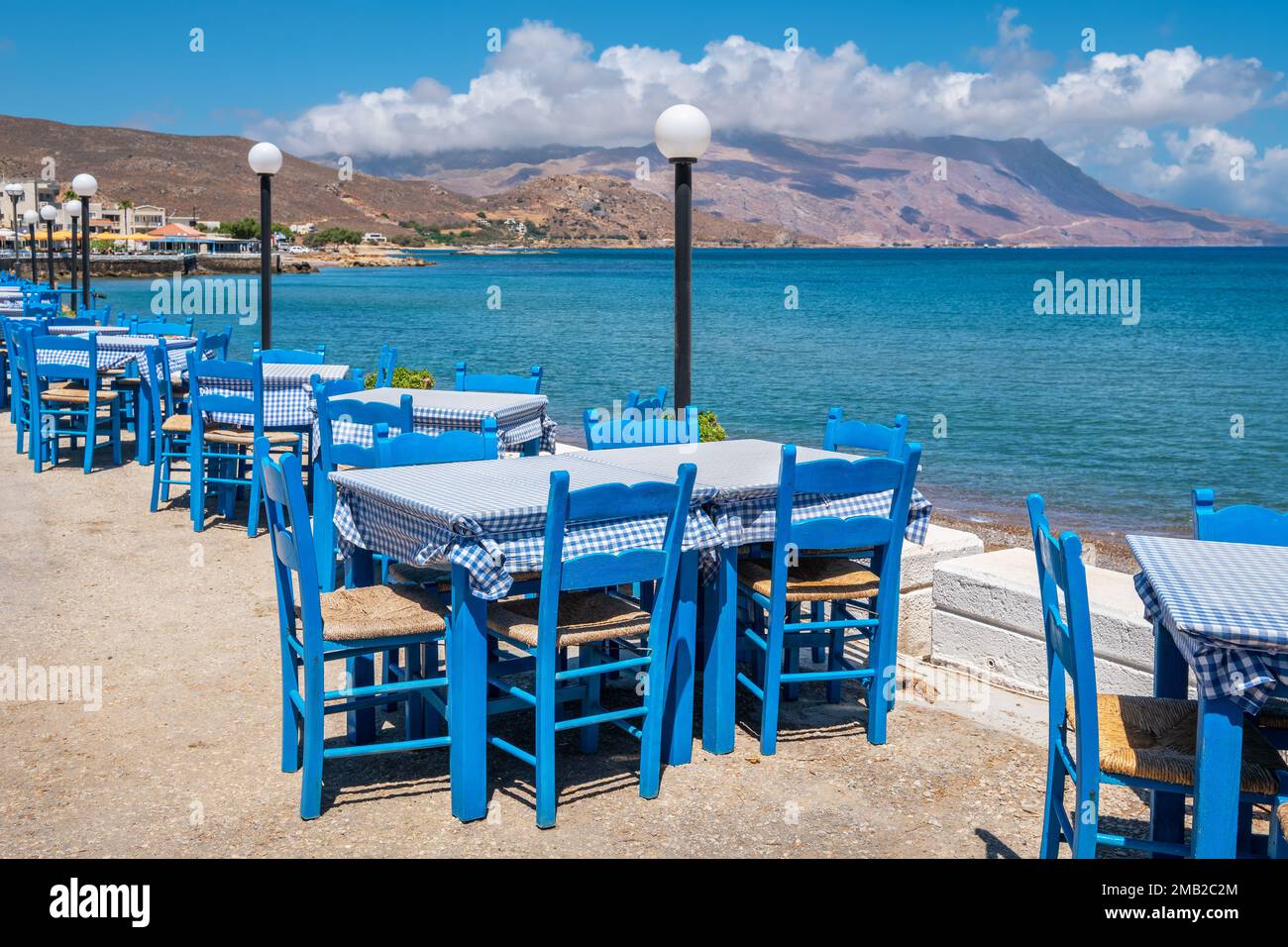 Blue tables and chairs in traditional Greek taverna on sea coast ...