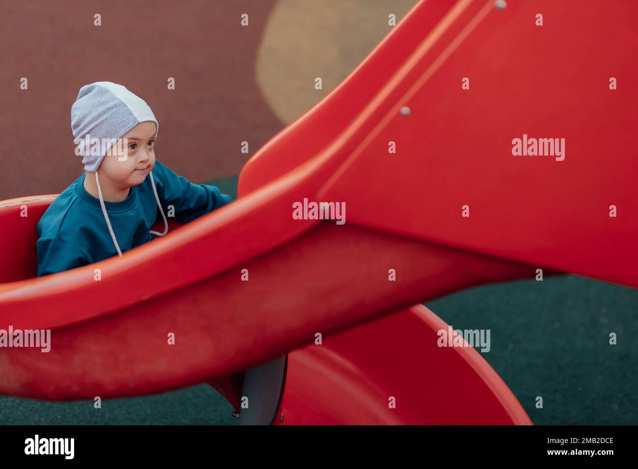Cute Little boy with down syndrome in hat walks in the playground ...