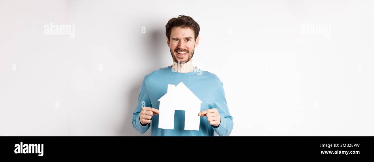 Real estate and insurance concept. Happy young man winking and smiling ...