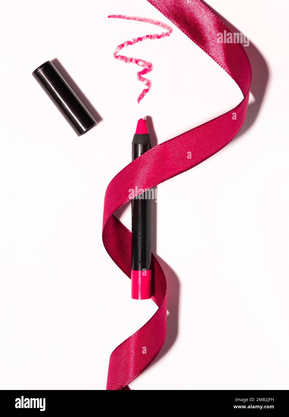 Red matte lipstick in the form of a pencil with red ribbon, smear ...