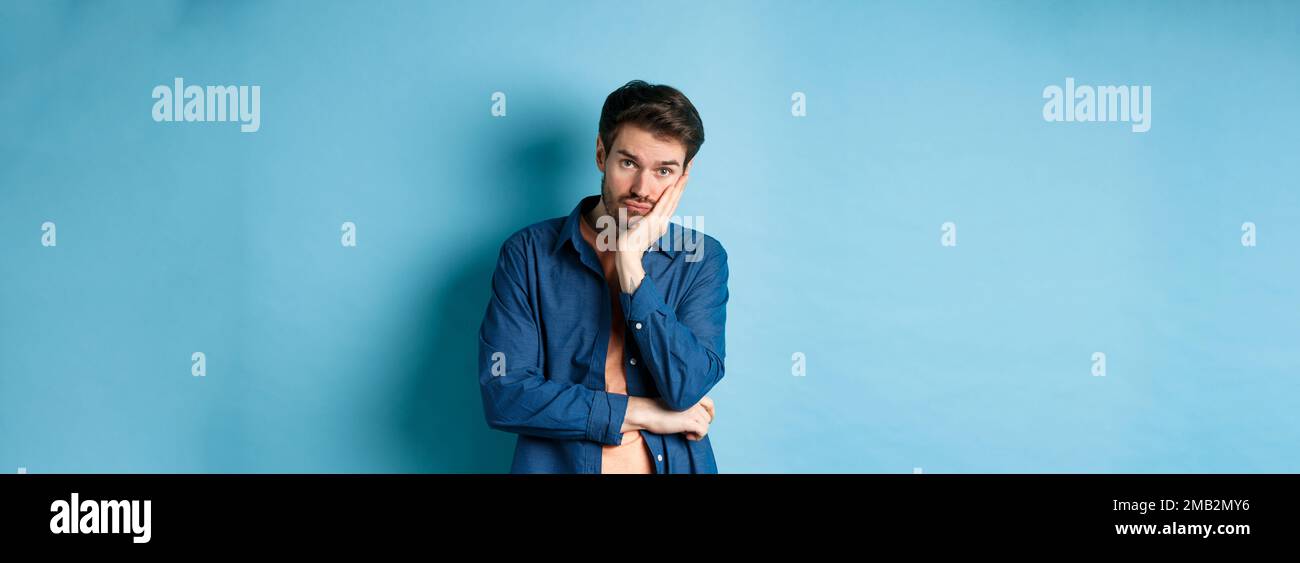 Sad and bored man lean face on hand, looking at camera empty-headed ...