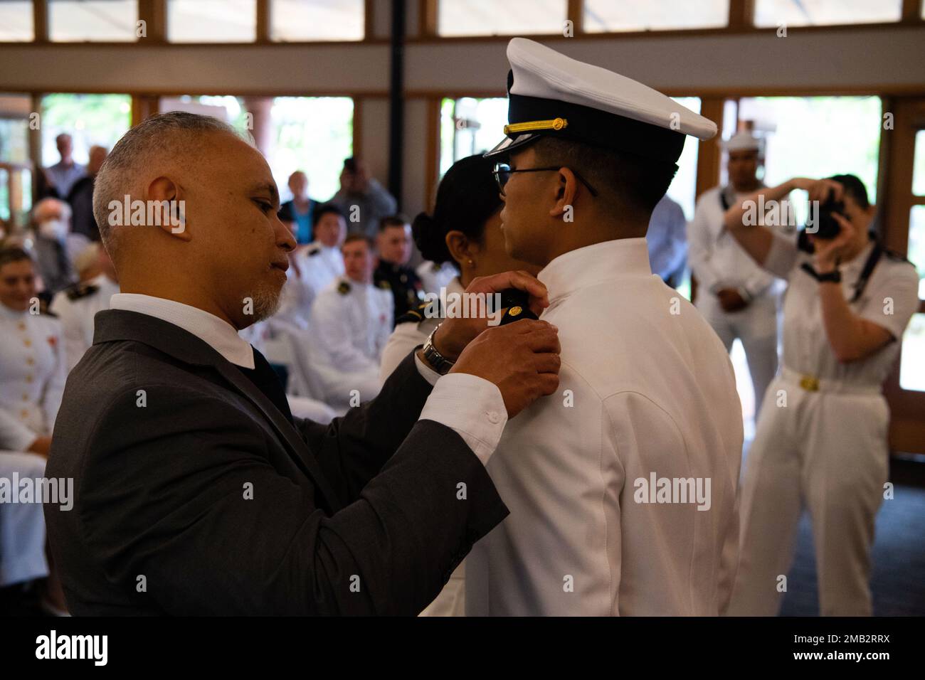 Ensign Jacob Castro's parents replace his shoulder boards during a ...