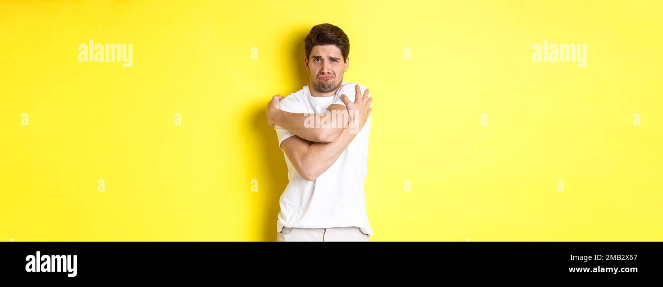 Silly and timid guy trying to comfort himself, hugging his body and ...