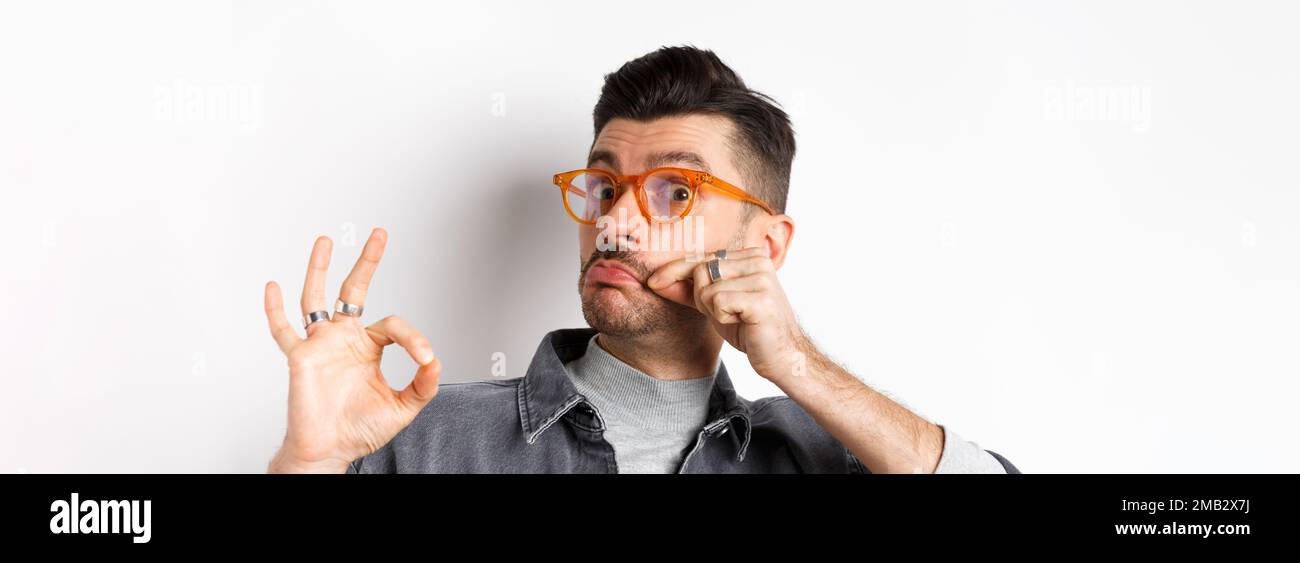 Funny young man in glasses touching his french moustache and showing ...