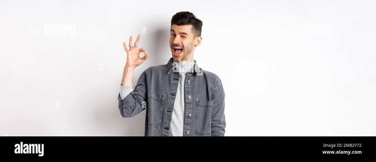 Excited handsome guy with moustache, winking and showing okay sign ...
