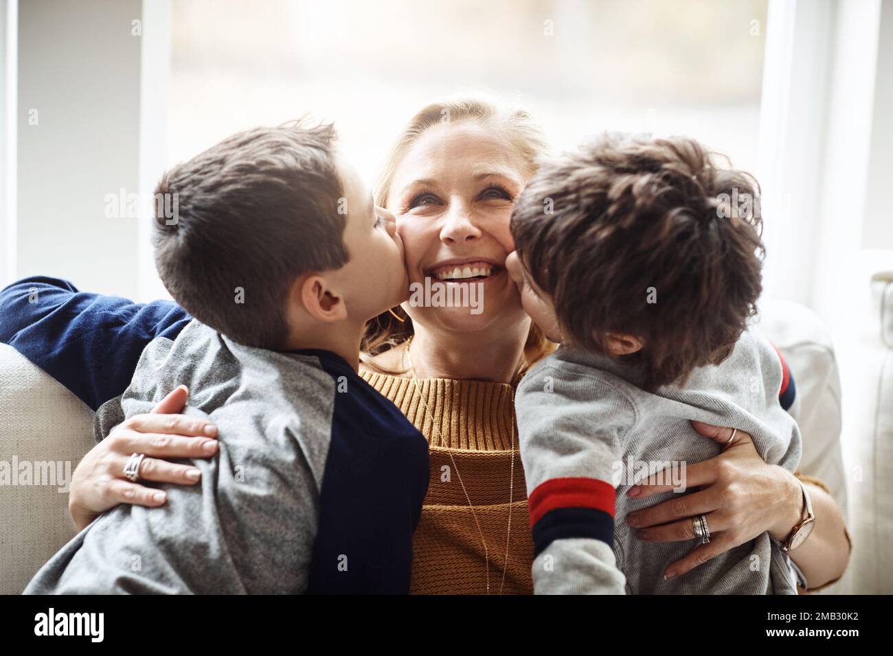 Kiss, bonding and a mother with children for love, relax and playing in ...